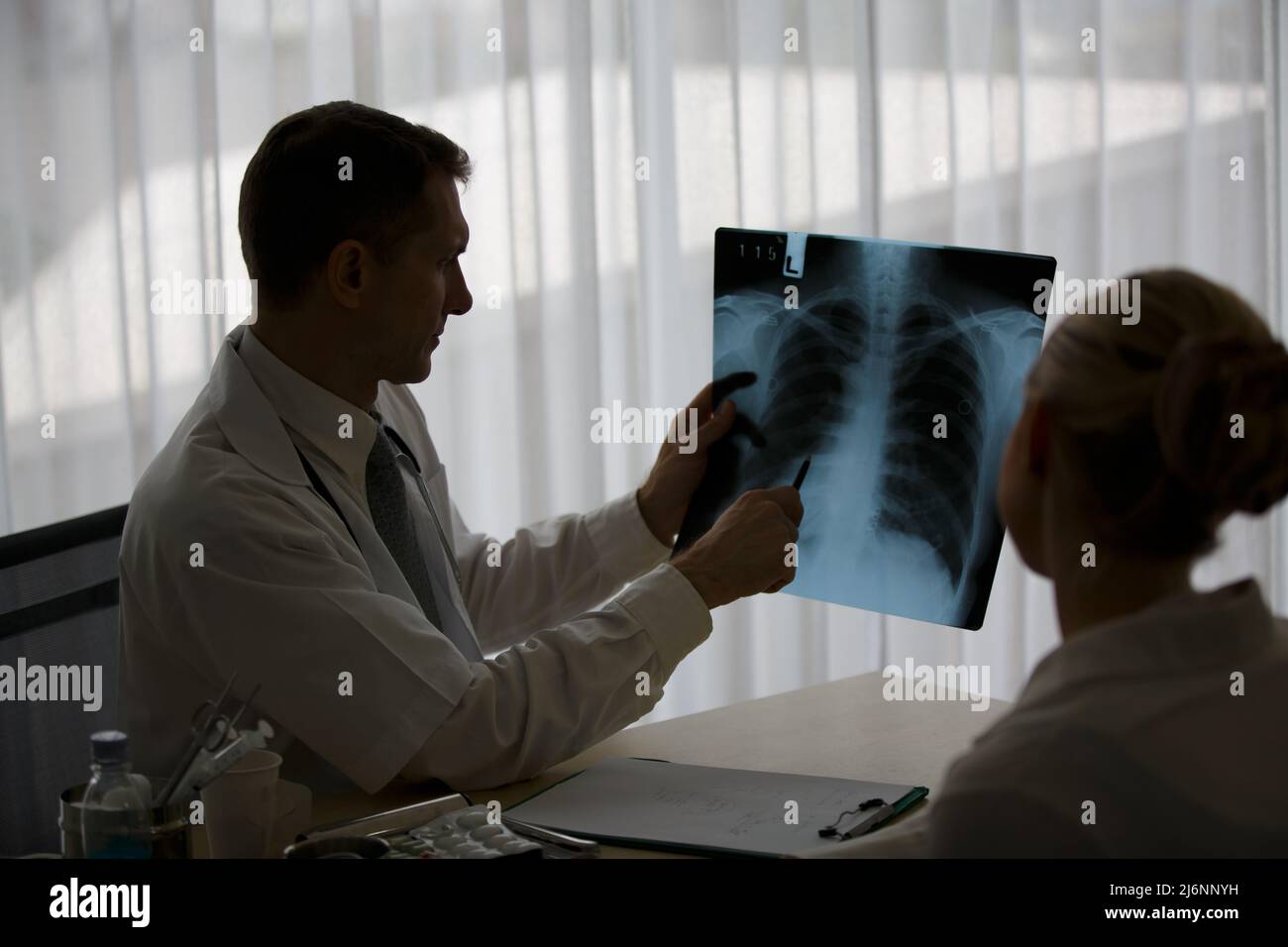 doctor looking on x-ray film woth patient in office Stock Photo - Alamy