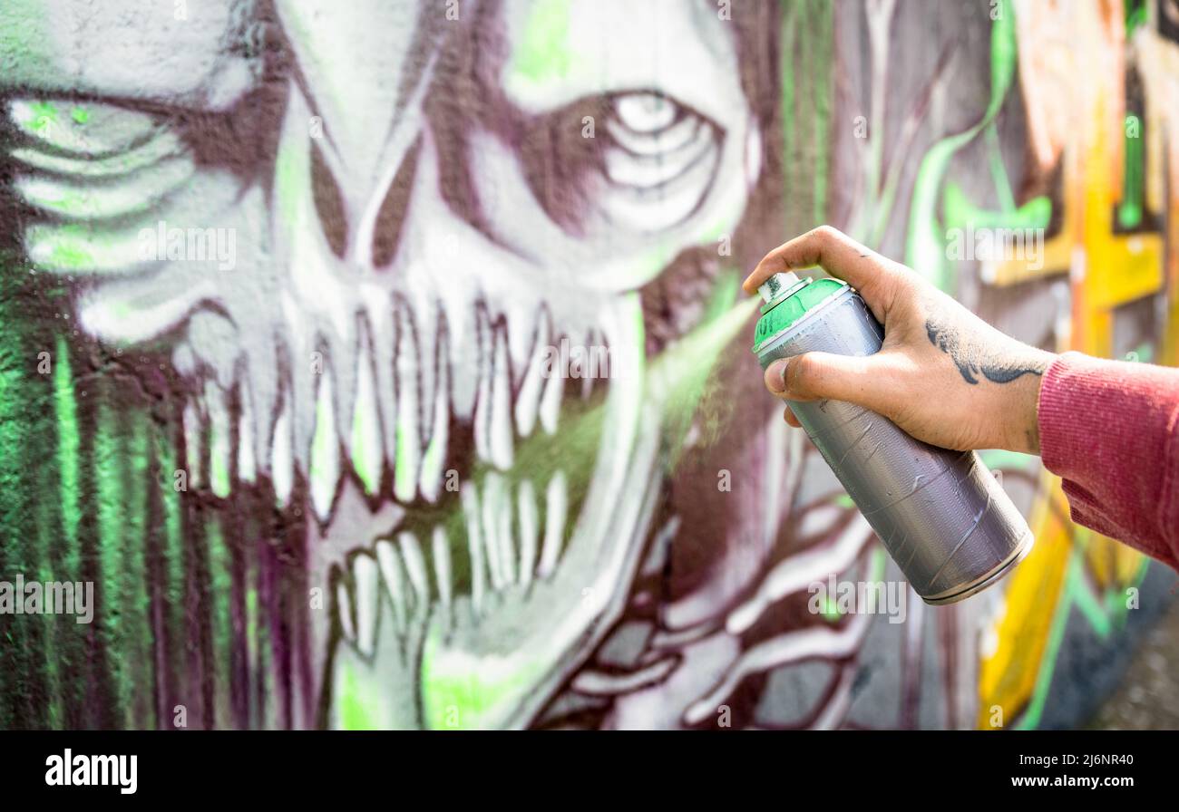 Street artist painting colorful monster graffiti on public wall ...