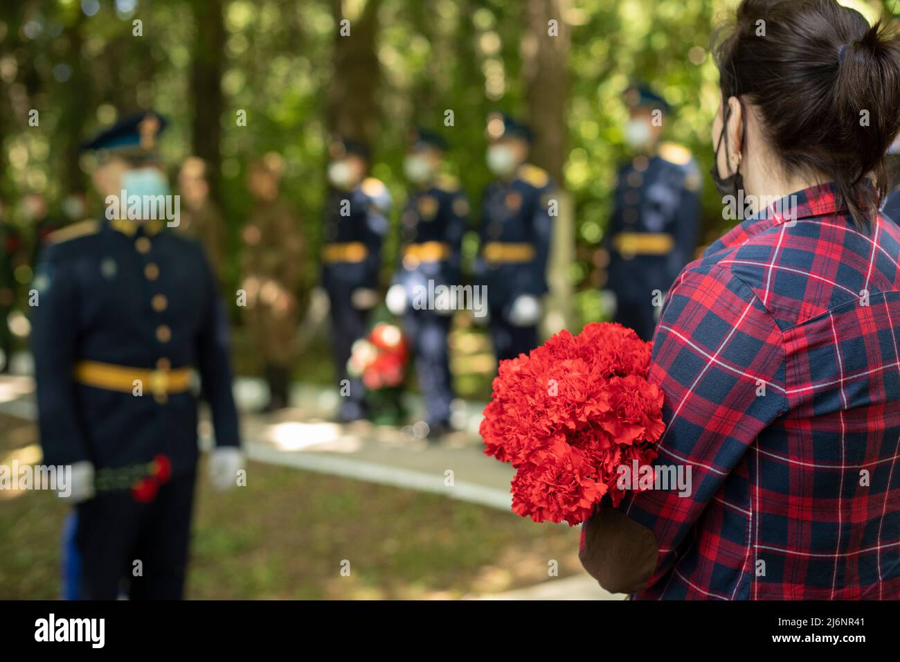 Flowers on memorial. Funeral of soldier. Girl at military ceremony. Red ...