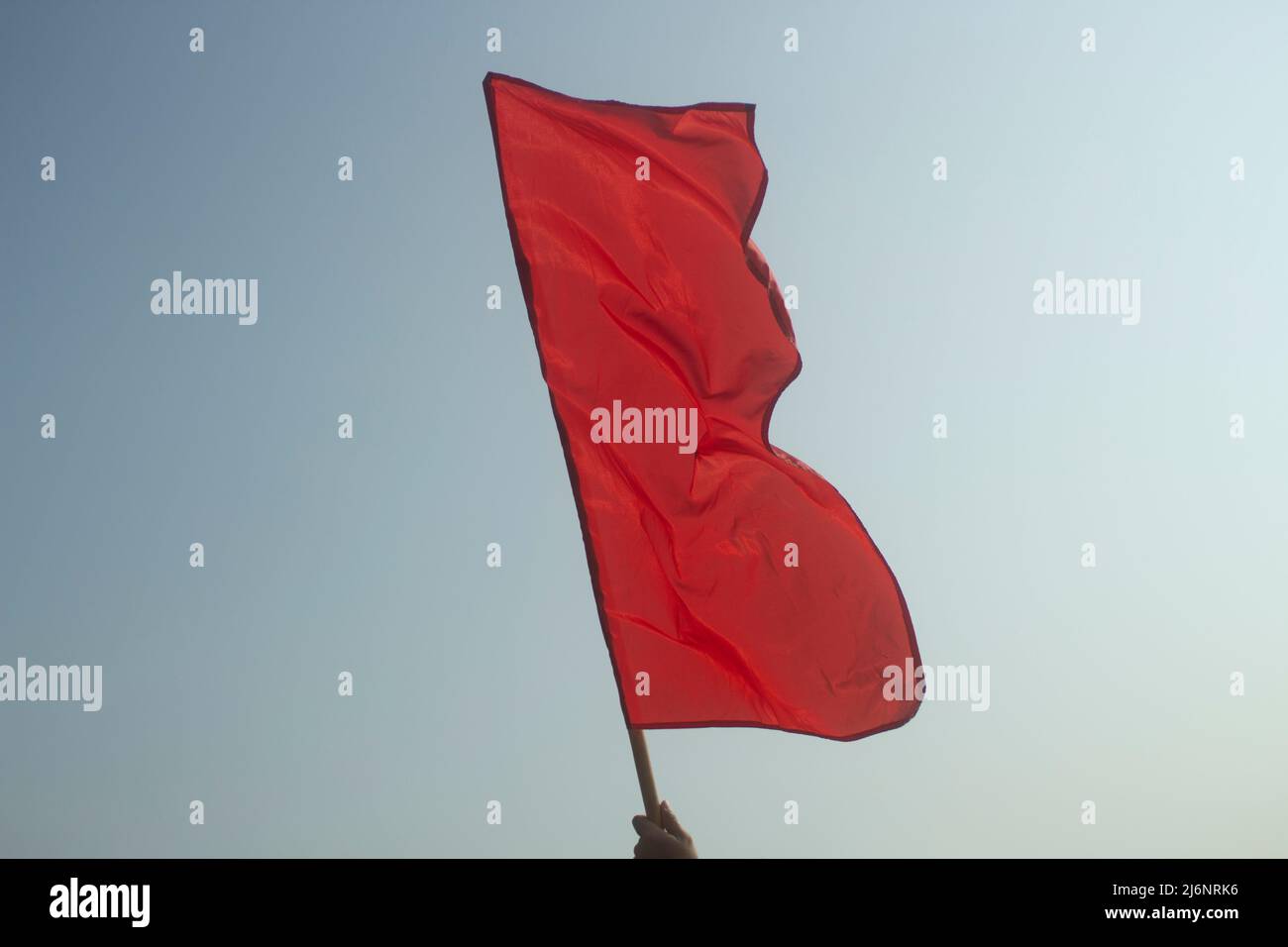 Red flag in his hand against sky. Red matter on pole. Signal to start ...