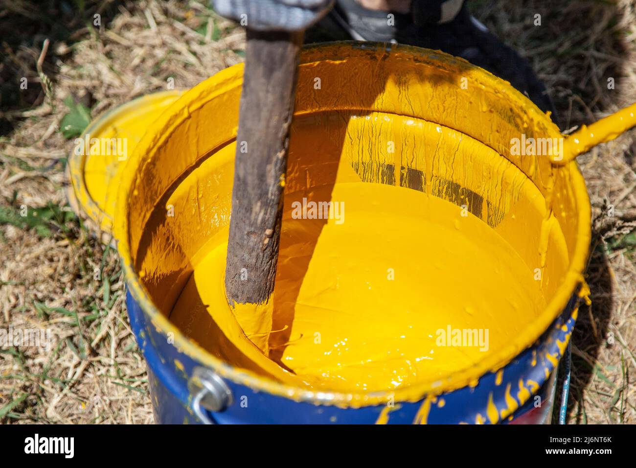 Yellow paint in bucket. Stirring paint in bucket. Preparation of ...