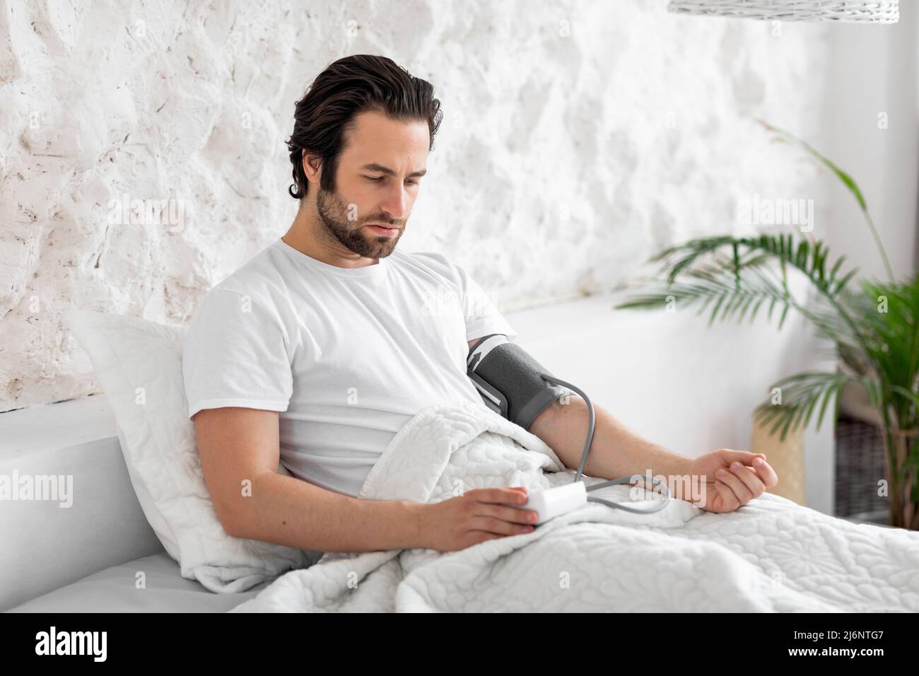 Young guy feeling unhealthy, measuring blood pressure Stock Photo - Alamy