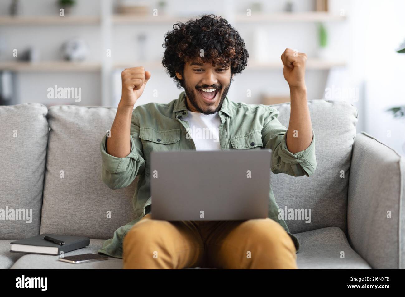Happy indian man with laptop raising hands up, home interior Stock ...