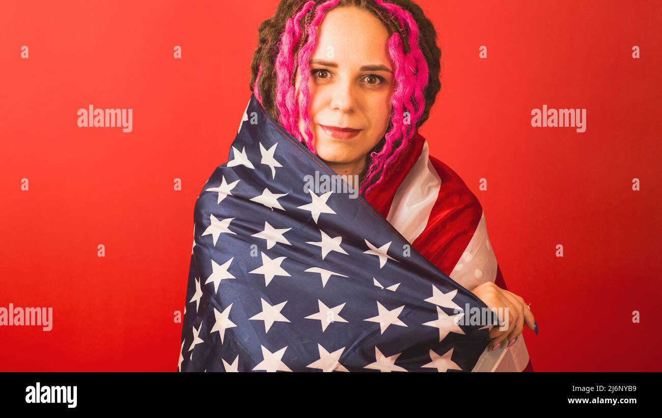 Young woman wrapped in American flag on red background. Happy female ...