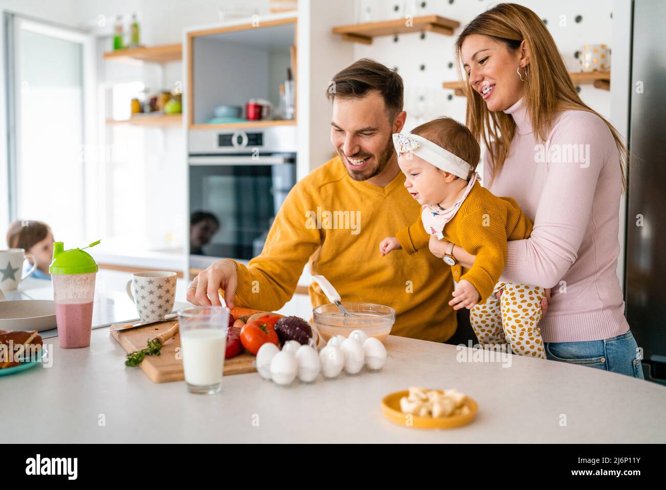 Little girl and his parents having fun and cooking together in the ...