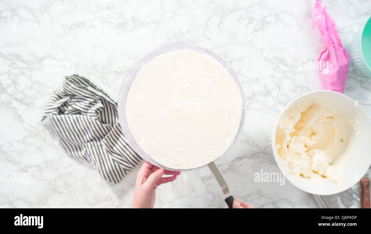 Flat lay. Step by step. Frosting round funfetti cake with white italian ...