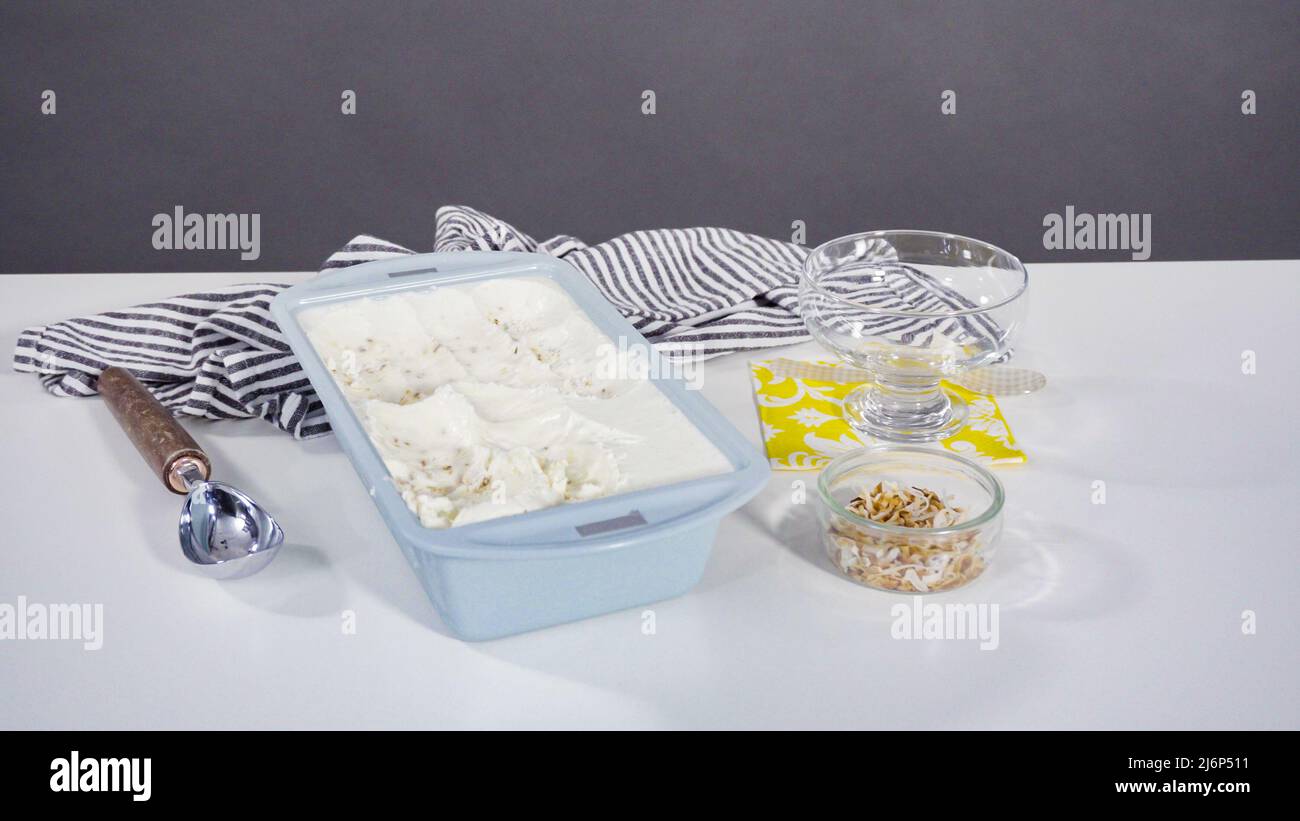 Scooping homemade coconut ice cream into a glass ice cream bowl Stock ...