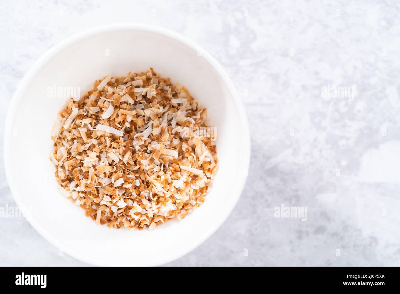 Toasted shredded coconut flakes in a white ceramic bowl Stock Photo - Alamy
