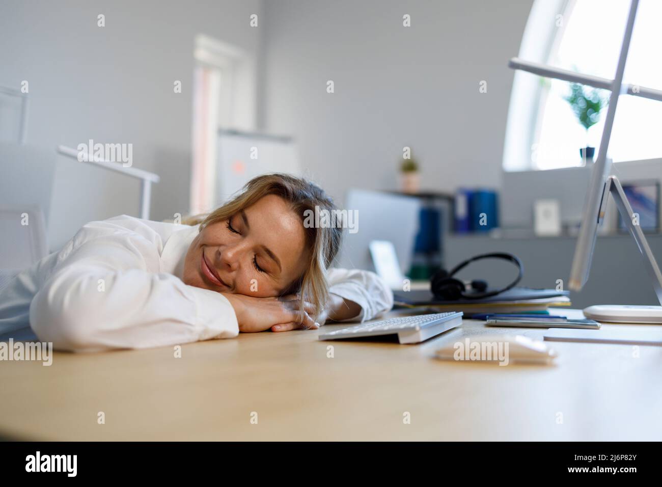 Middle aged business woman taking a nap right at the workplace ...