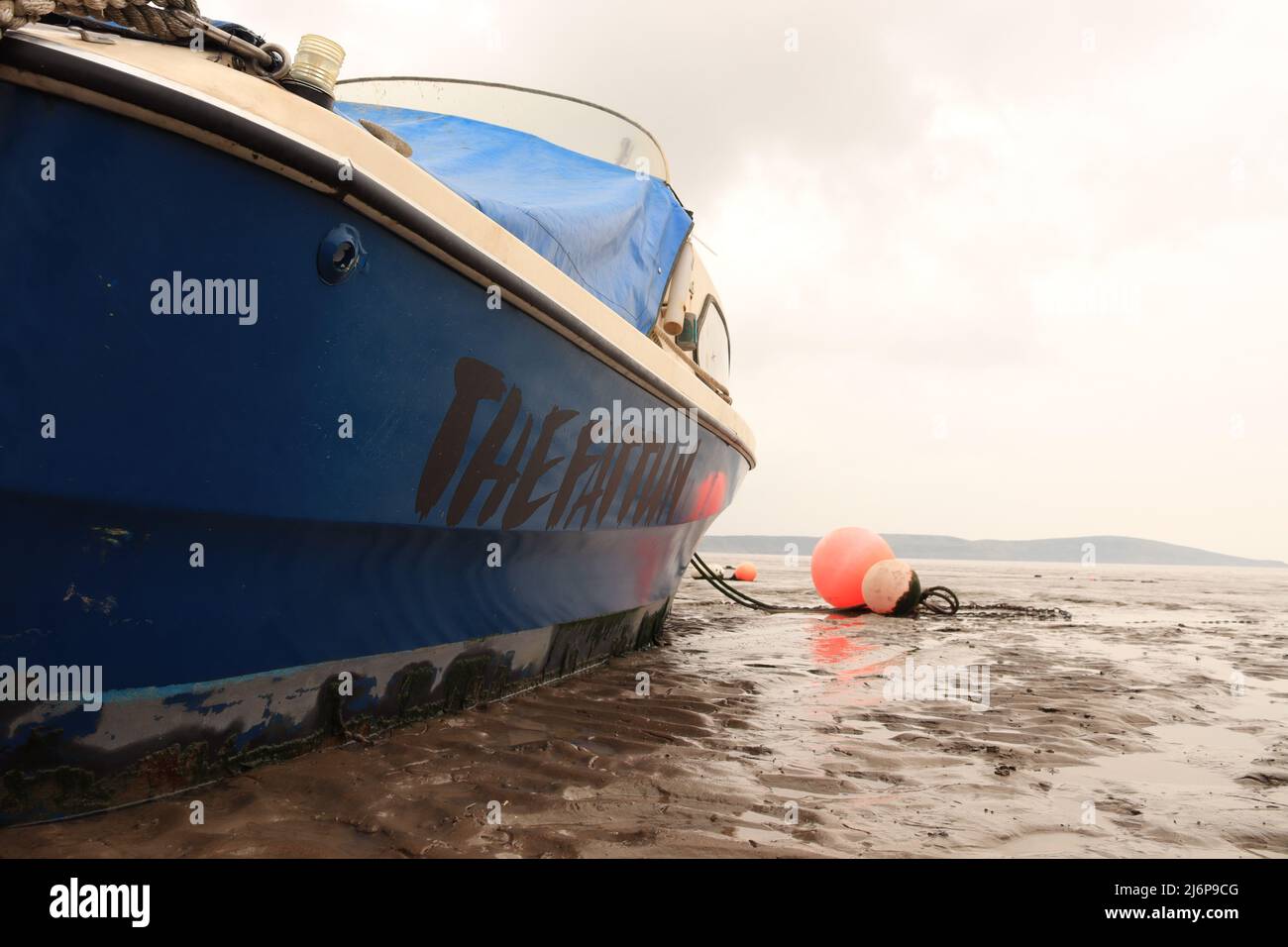 Blue Hull boat stuck in the mud Stock Photo - Alamy