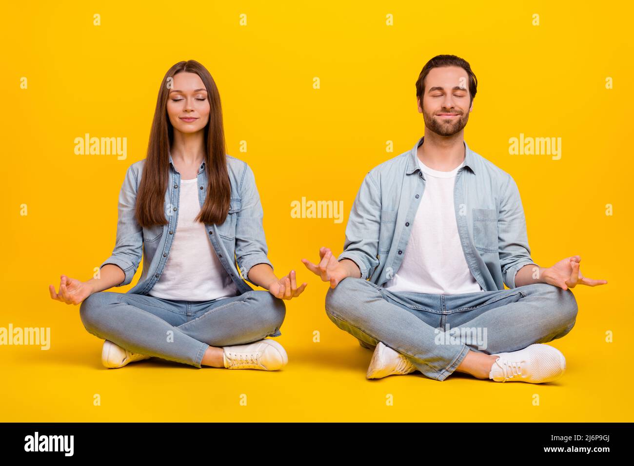 Portrait of attractive dreamy couple sitting meditating om zen isolated ...
