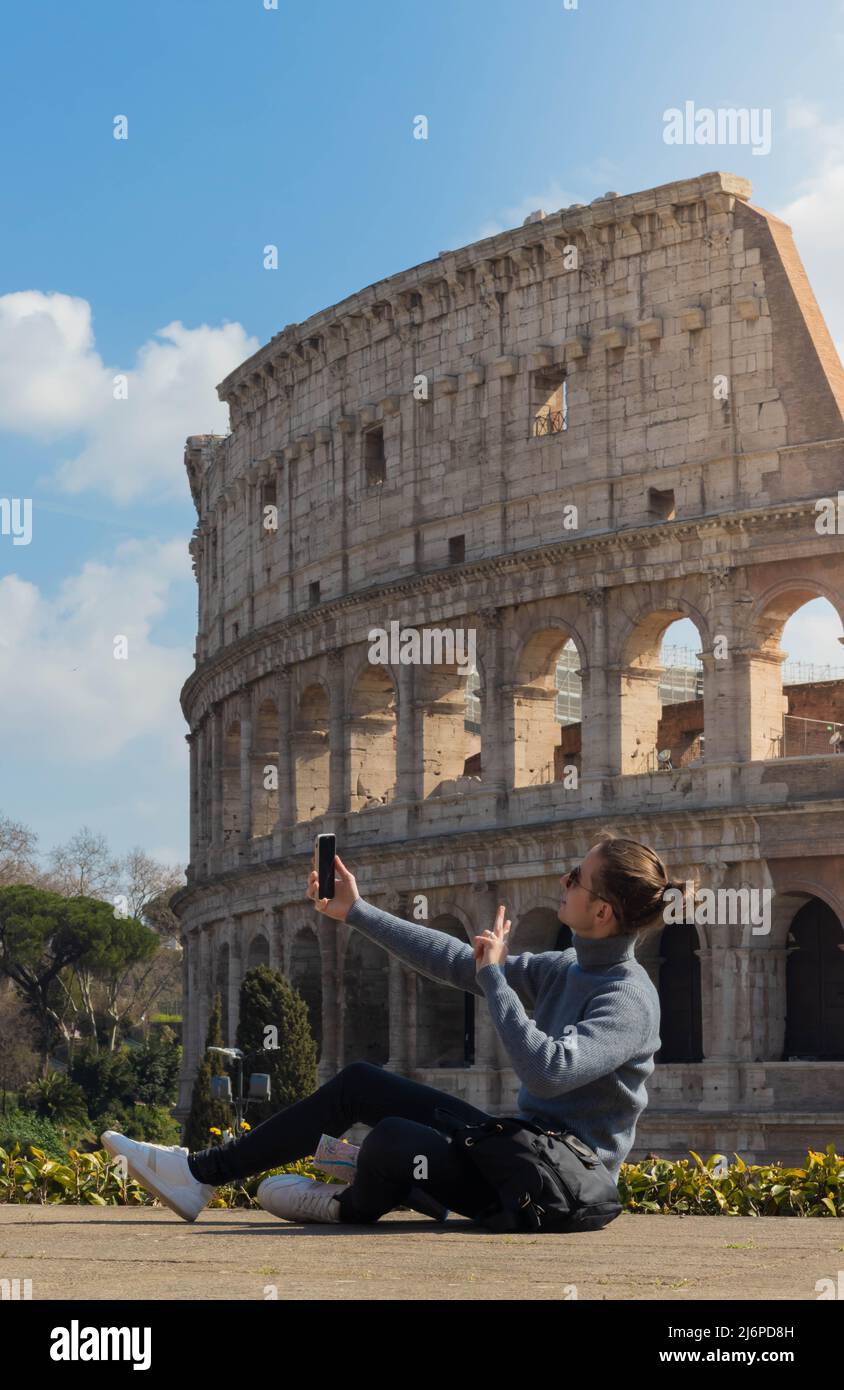 Young man taking a selfie photo and waving with the Colosseum of Rome ...