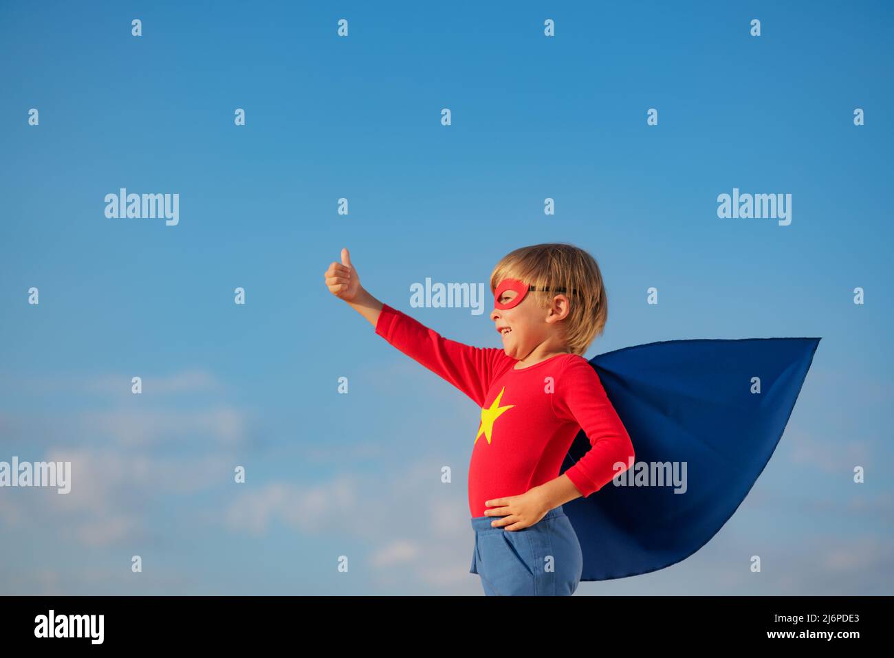 Superhero child playing outdoor. Super hero kid against blue summer sky ...
