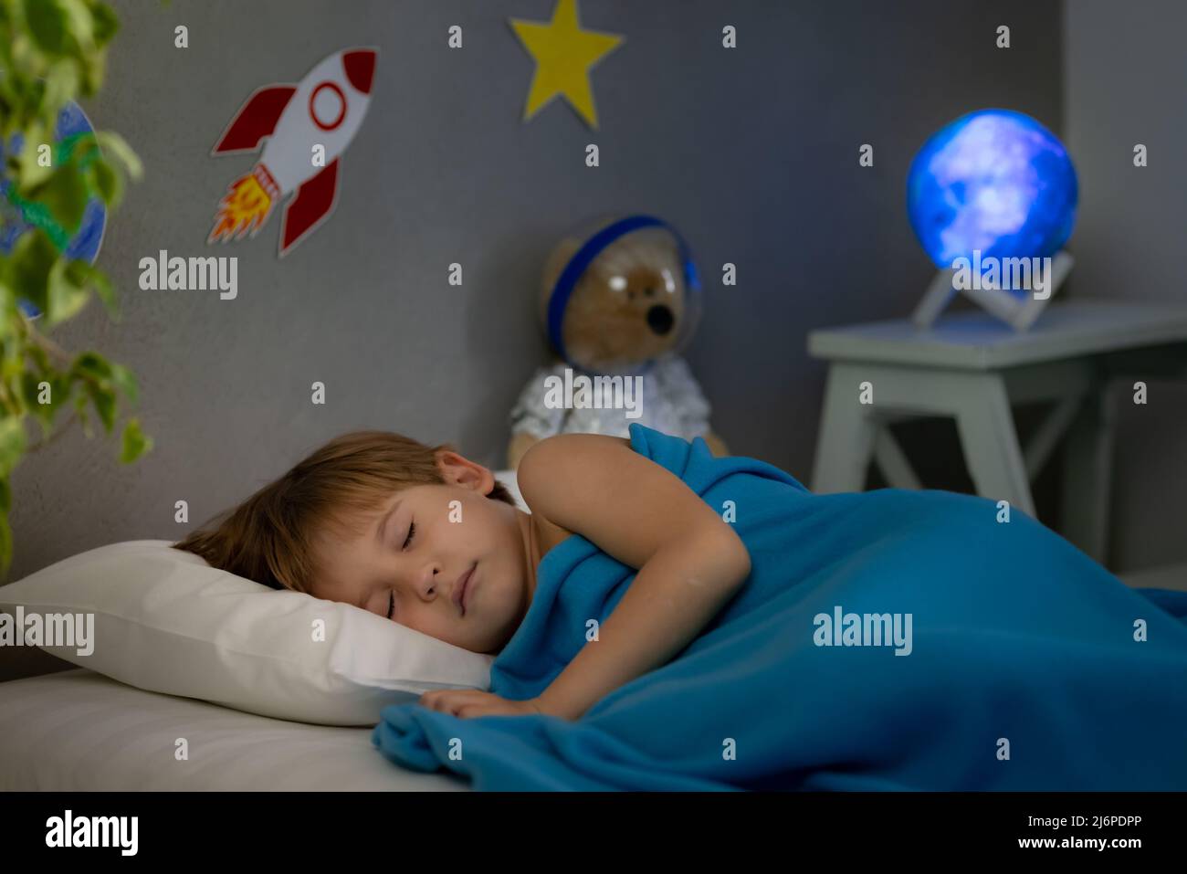 Happy child sleeping with toy rocket and teddy bear. Kid pretend to be ...