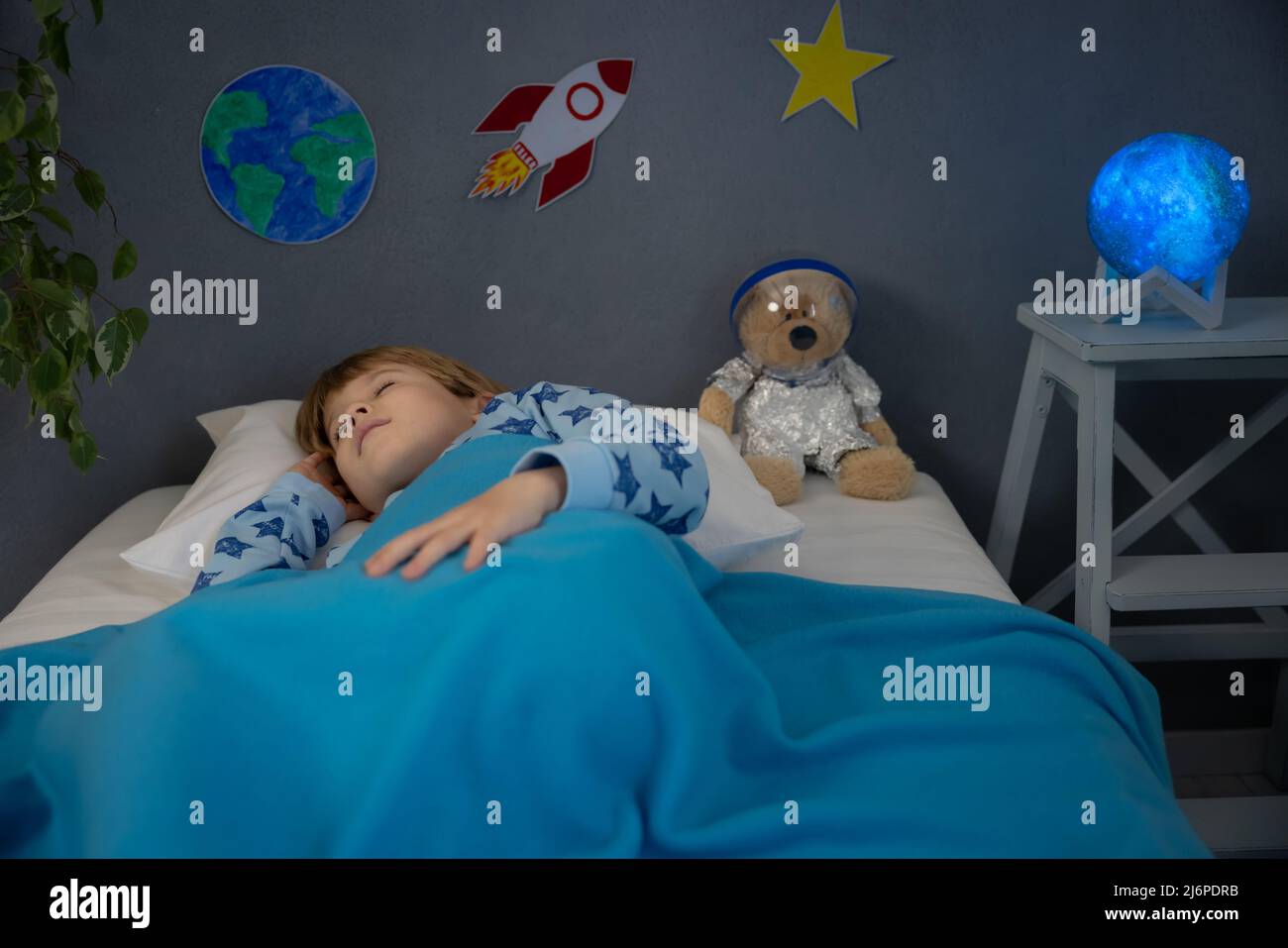Happy child sleeping with toy rocket and teddy bear. Kid pretend to be ...