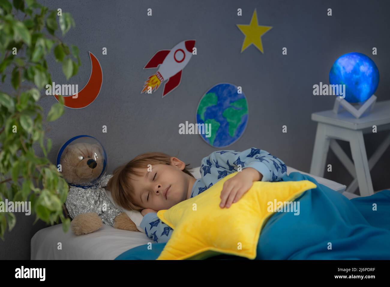 Happy child sleeping with toy rocket and teddy bear. Kid pretend to be ...