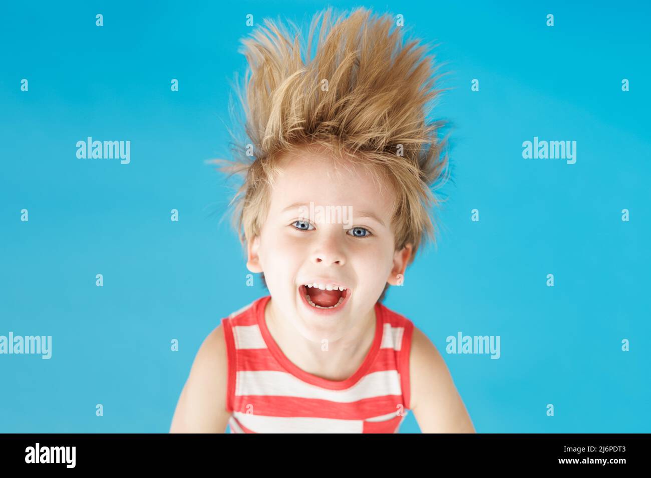 Happy child shouting against blue paper background. Funny kid hanging ...