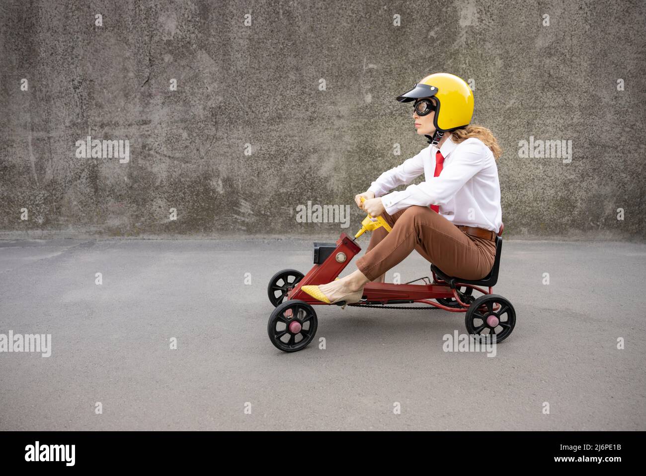 Portrait of funny businesswoman outdoor. Woman driving retro pedal car ...