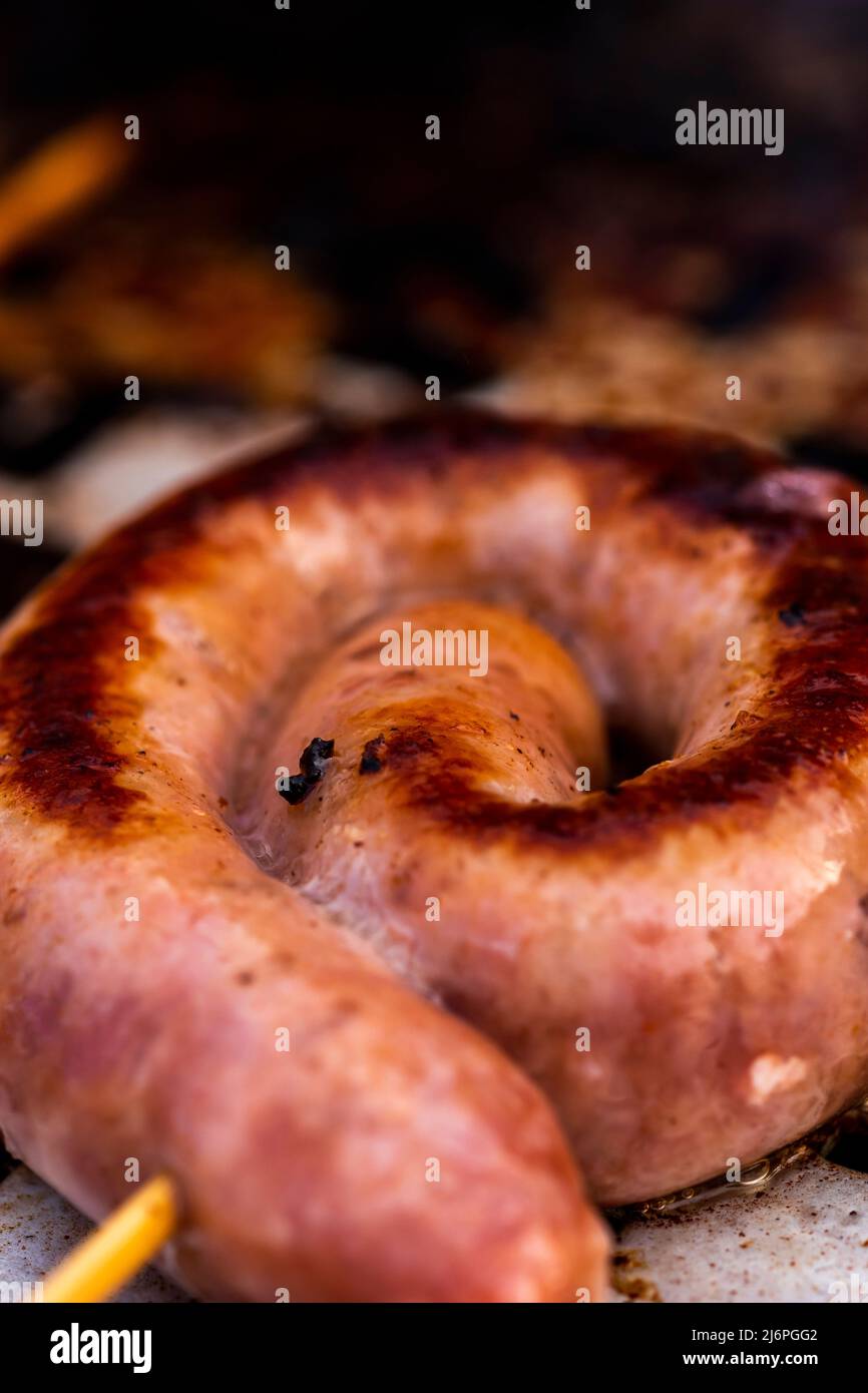 Close up shot of rolled up sausages on skewer placed over barbeque Stock Photo - Alamy