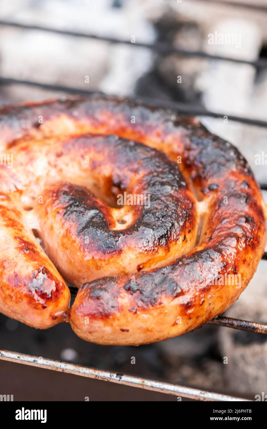 Close up shot of rolled up sausages on skewer placed over barbeque Stock Photo - Alamy