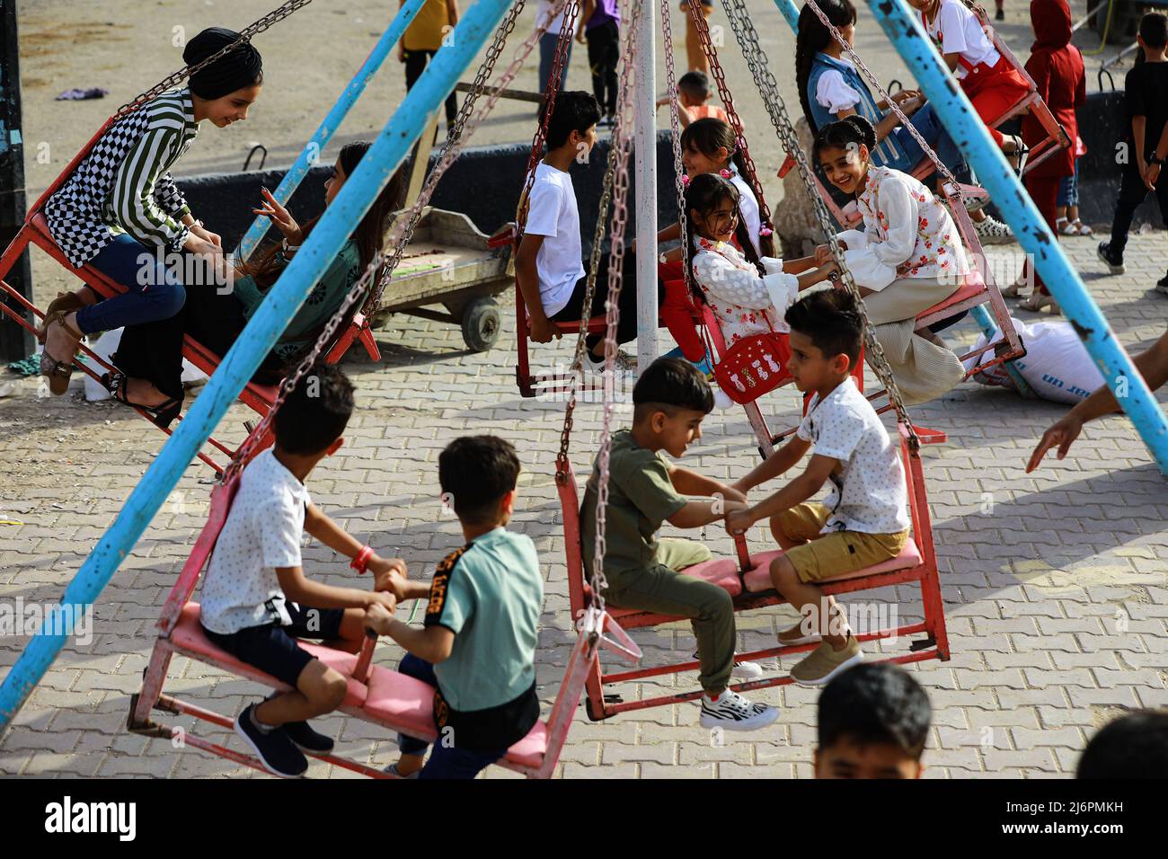 03 May 2022, Iraq, Baghdad: Children play on the swings at an amusement ...
