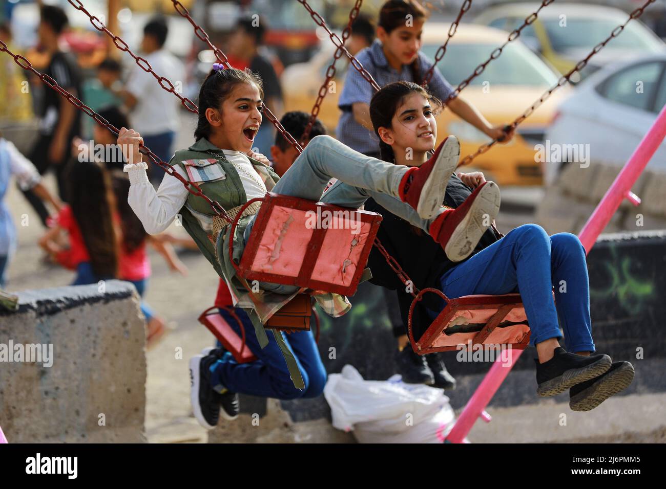 03 May 2022, Iraq, Baghdad: Children play on the swings at an amusement ...