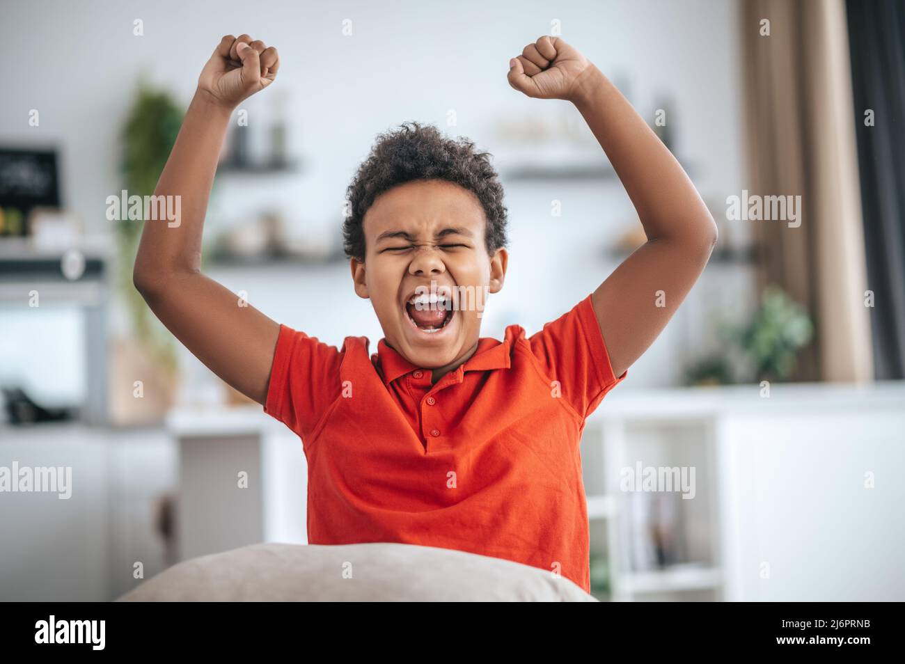 A cute boy raising his hands and looking excited Stock Photo - Alamy