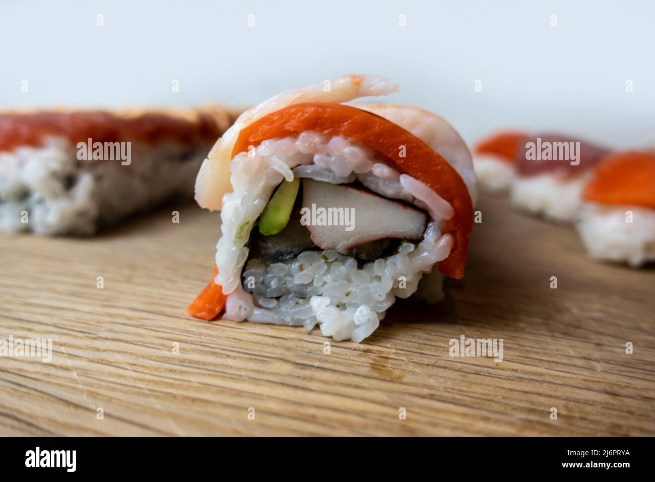 Angled, selective focus view of a variety of sushi rolls on a bamboo ...