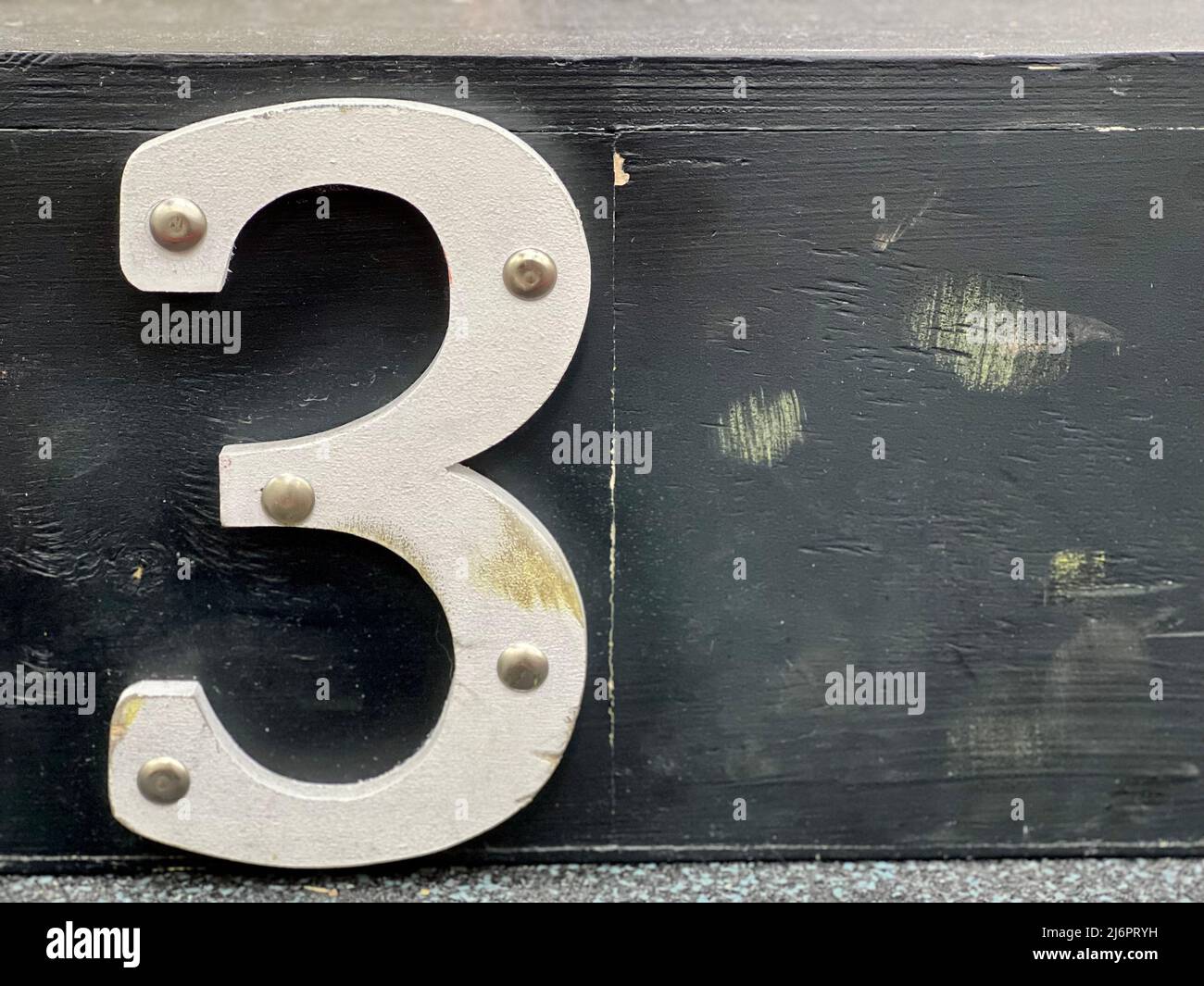 White wooden number three with nail heads on black background, copy ...