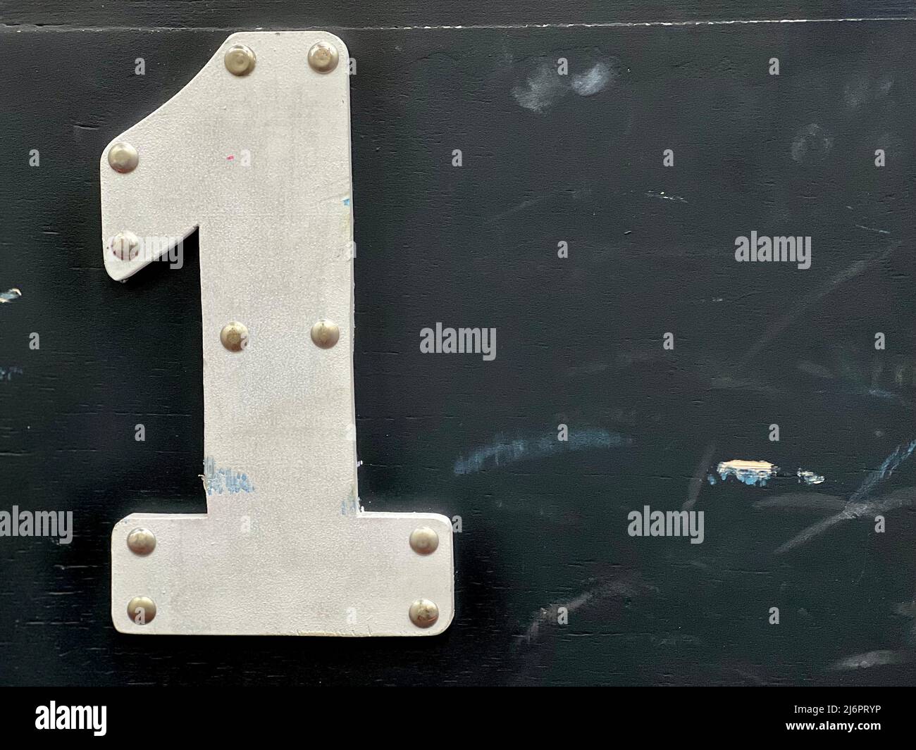 White wooden number one with nail heads on black background, copy space ...