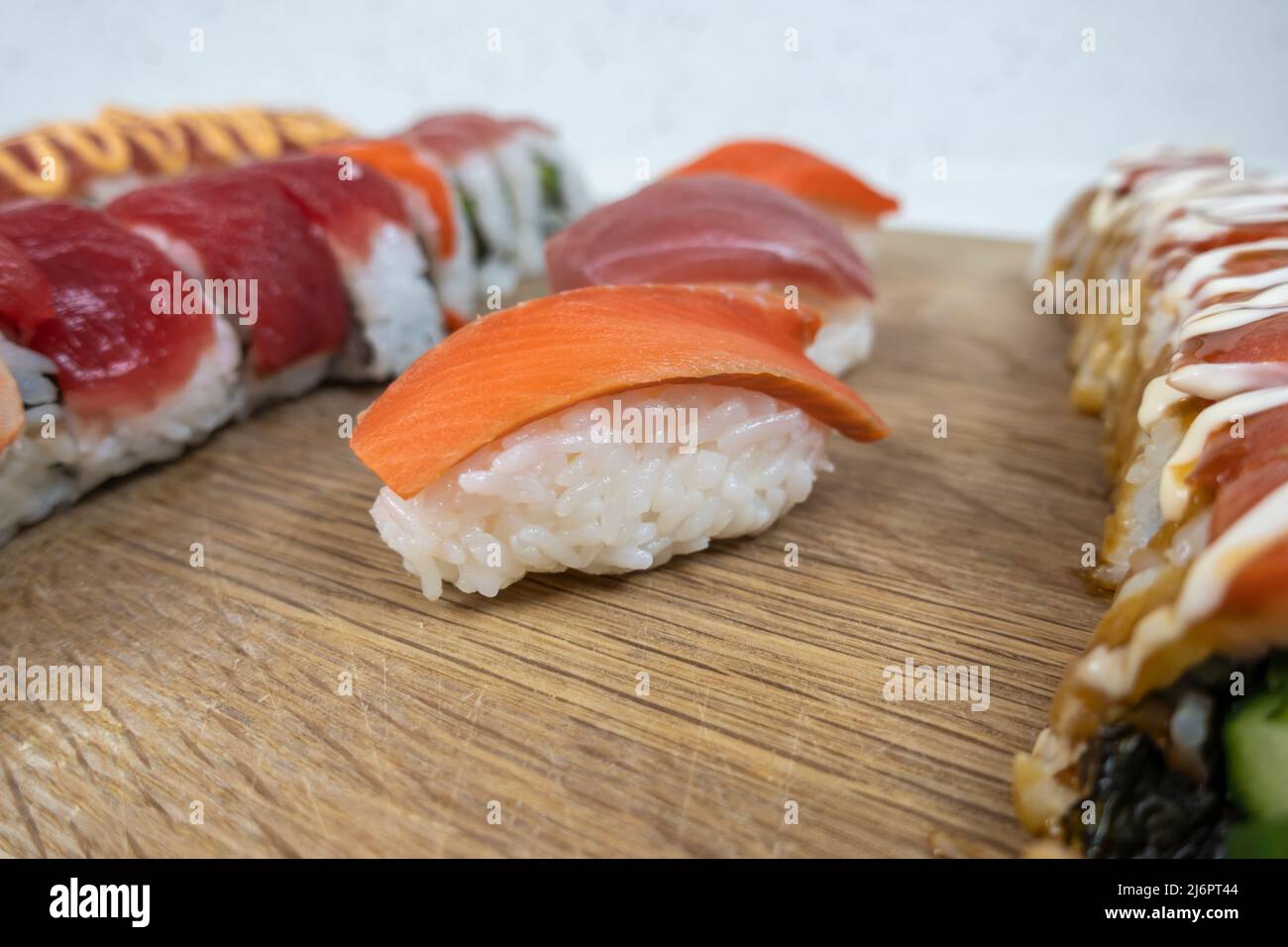 Angled, selective focus view of a variety of sushi rolls on a bamboo ...