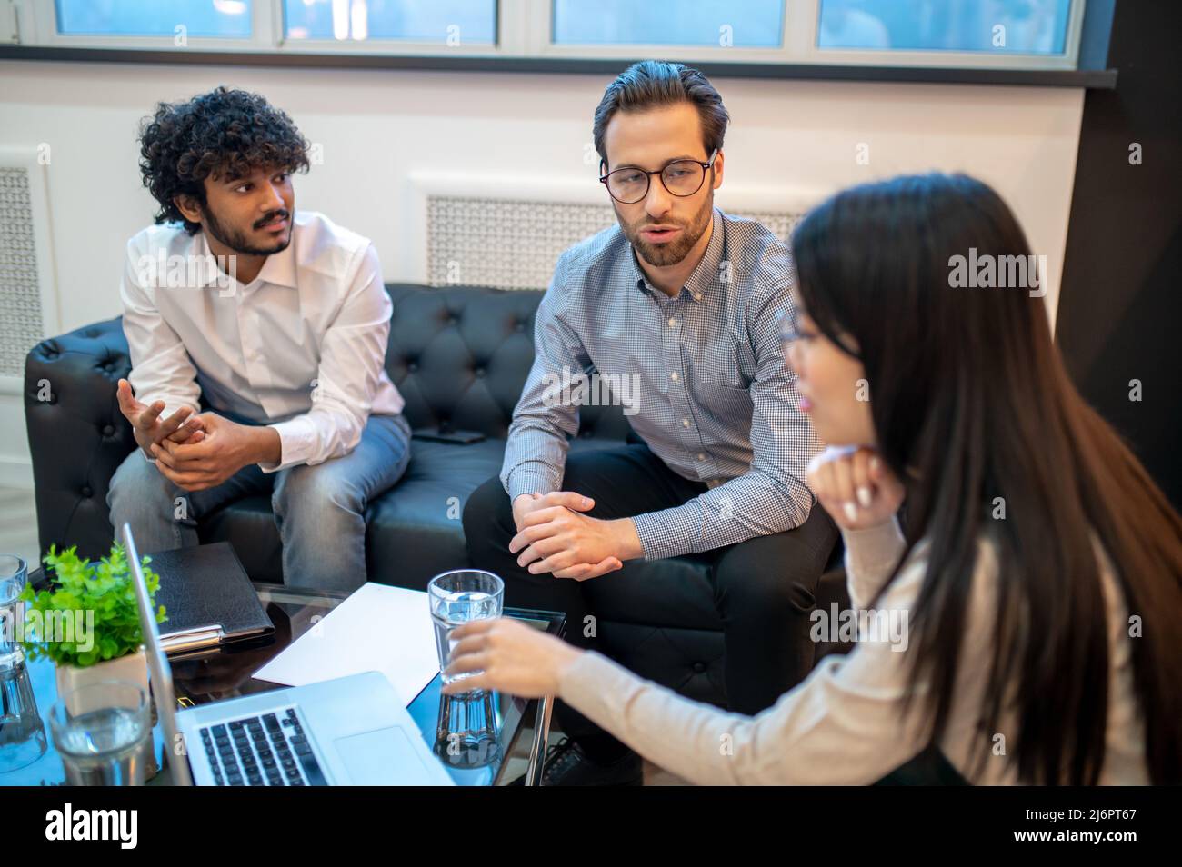 Three company employees sitting around the table Stock Photo - Alamy