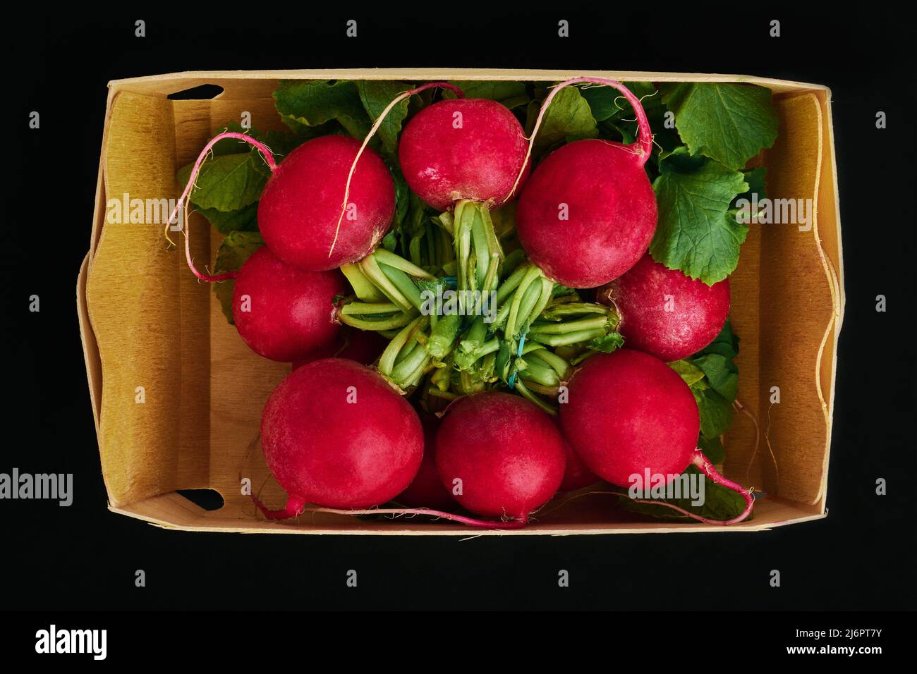 Bunch of radishes in wooden tray close-up, black background Stock Photo ...