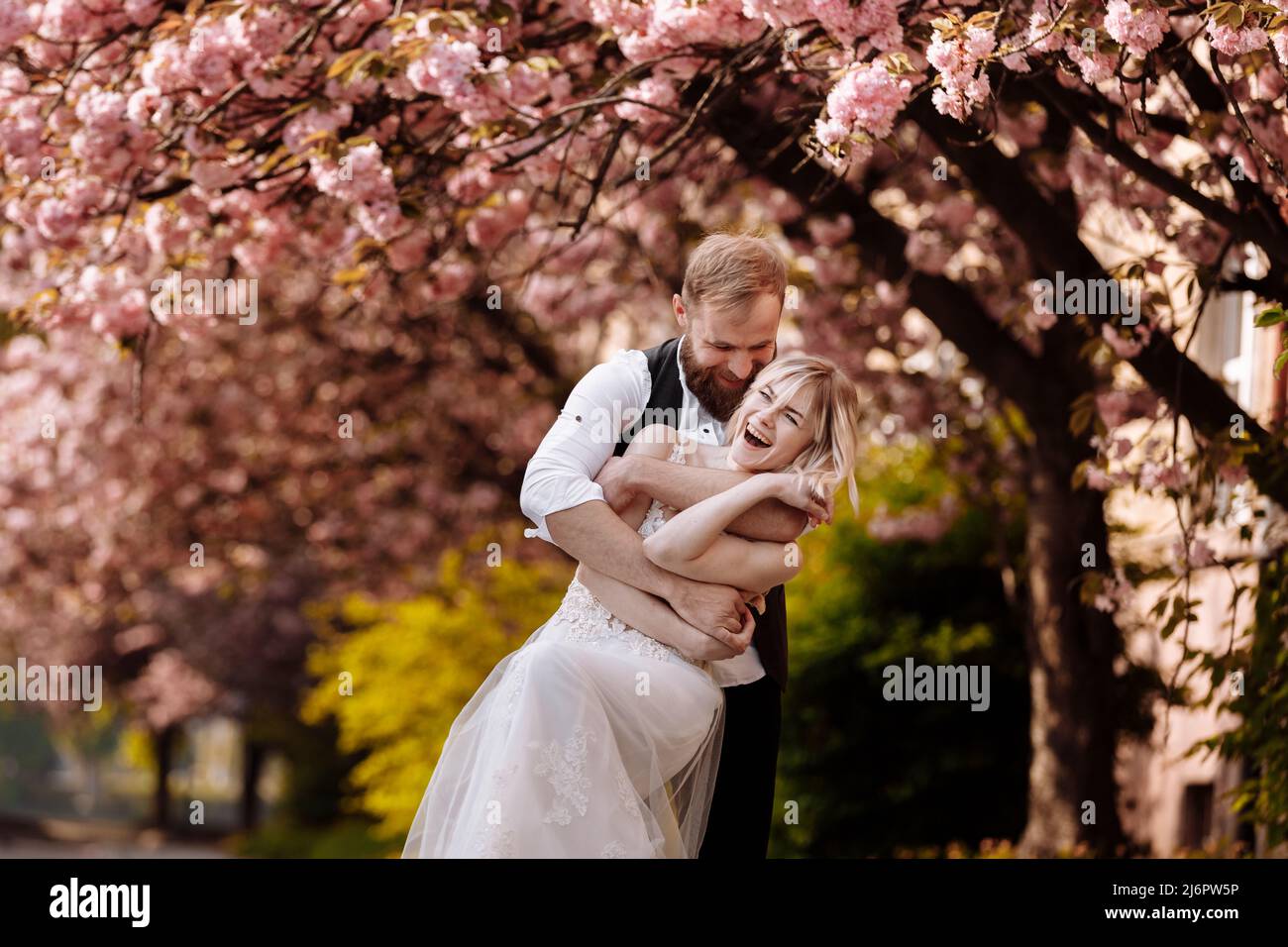 Beautiful, cheerful and lively newlyweds, groom and bride are hugging ...