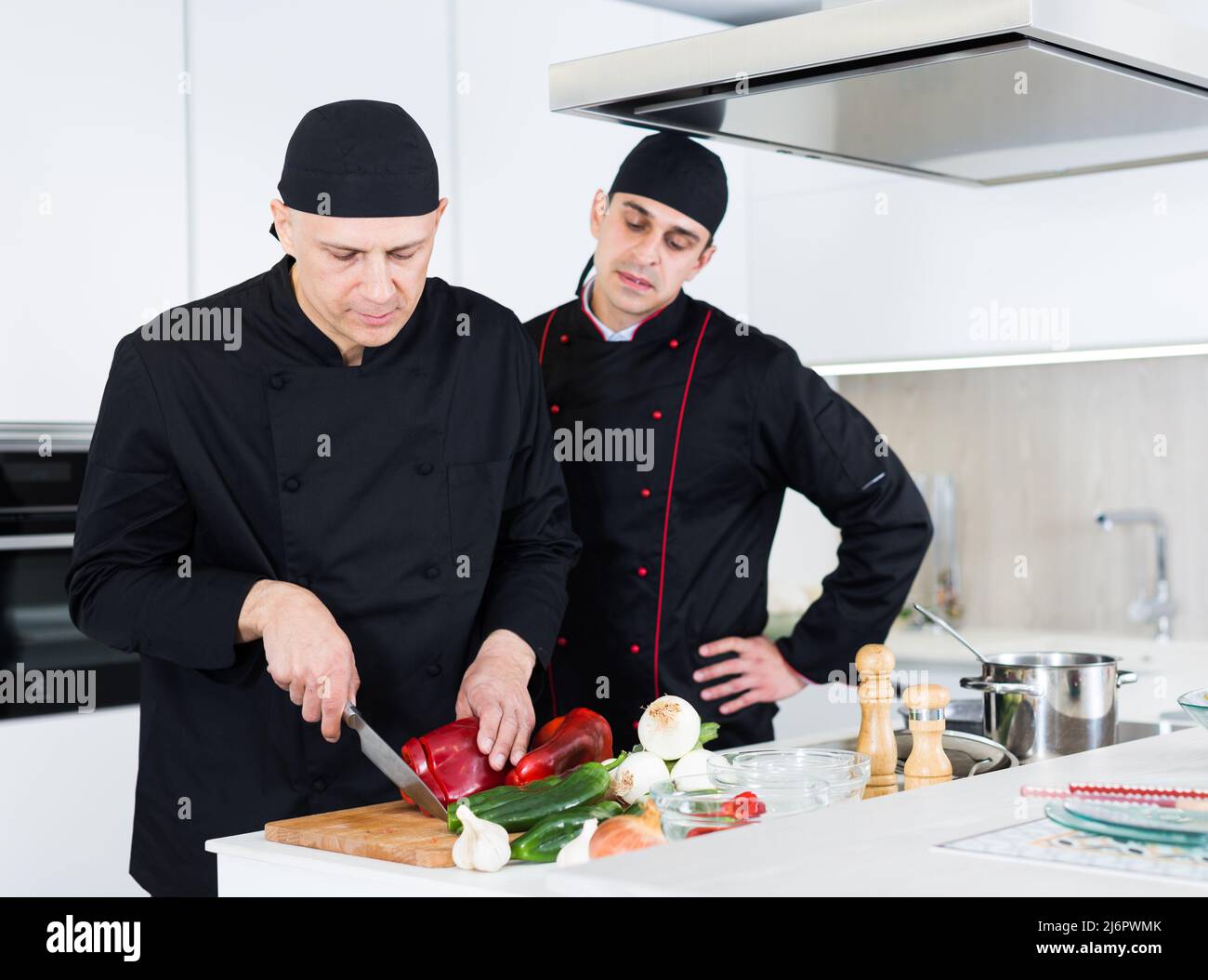 Professional men chefs in black uniform working together Stock Photo ...