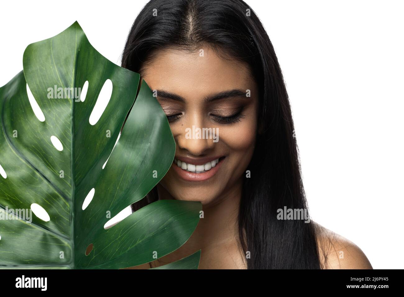 Beautiful Indian woman with a smooth skin holding green tropical leaf ...