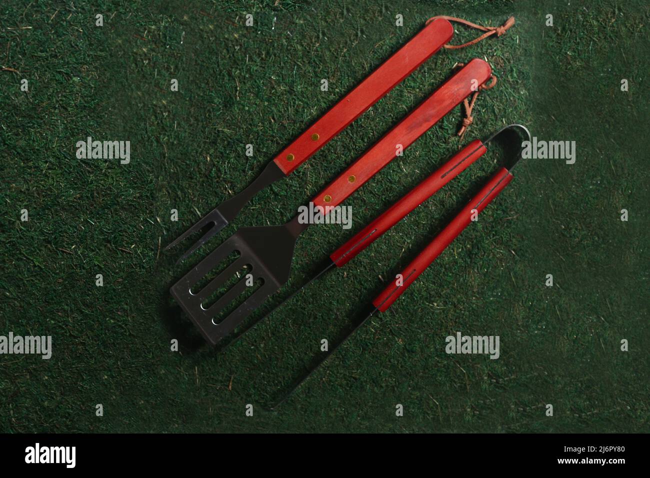 BBQ instruments kit - tongs, spatula, fork - close up isolated on green ...