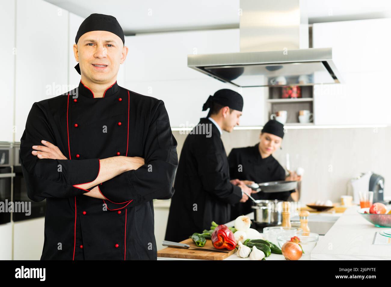 Portrait of man cook who is standing on his work place in the kitchen ...