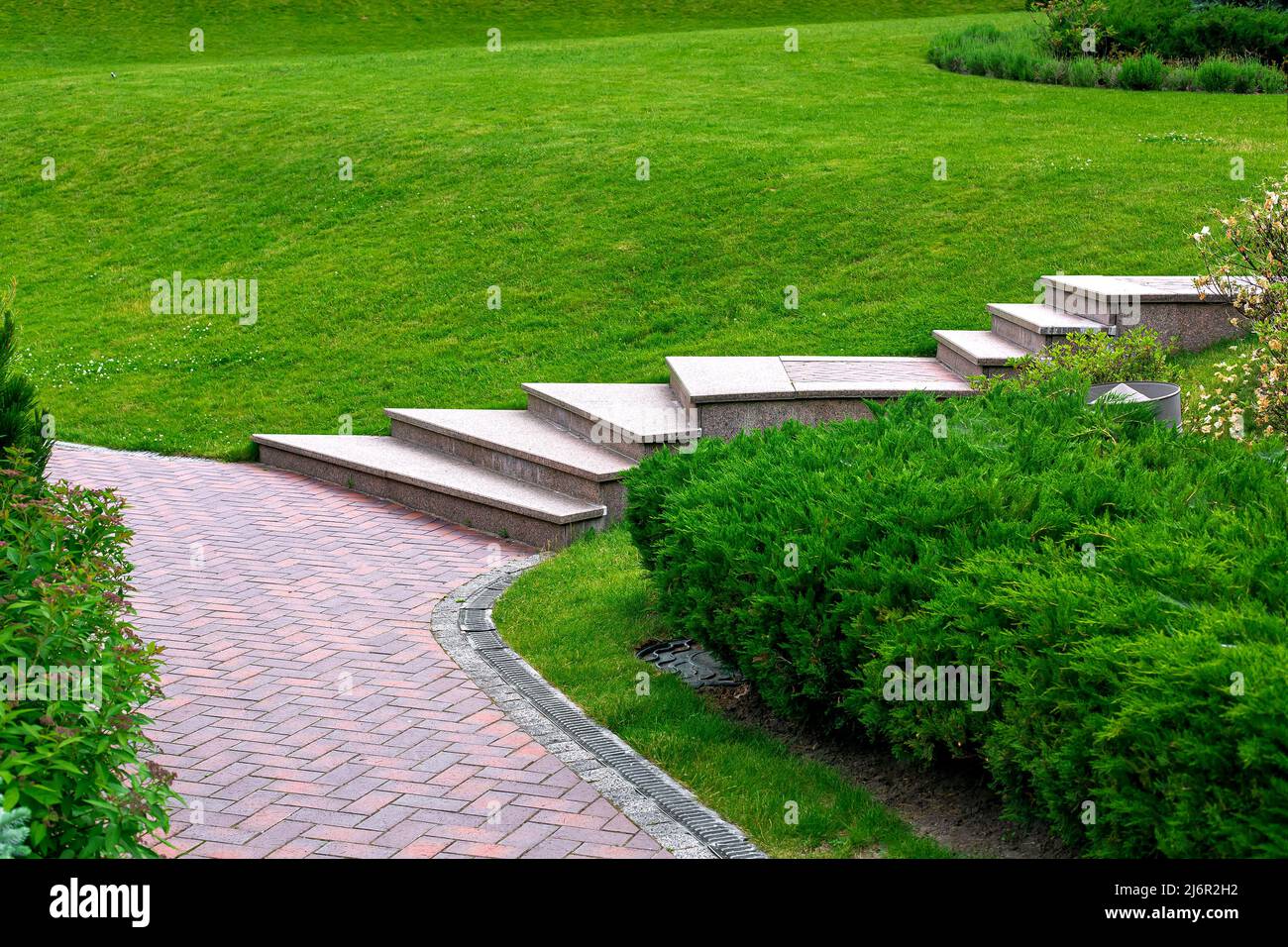 Granite steps to path from brick stone tile in a park on a slope with ...