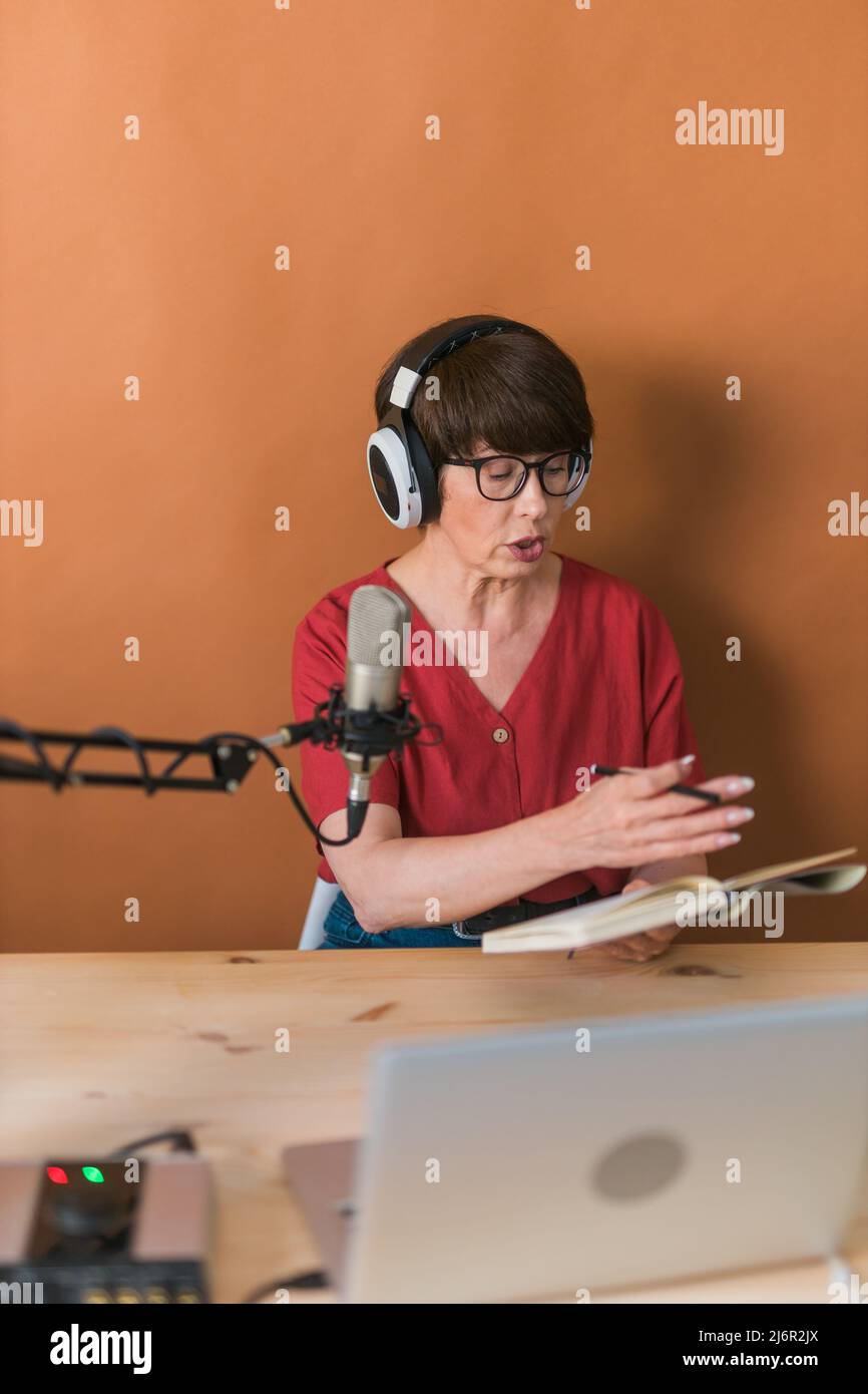 Middle-aged female radio presenter talking into the microphone and ...