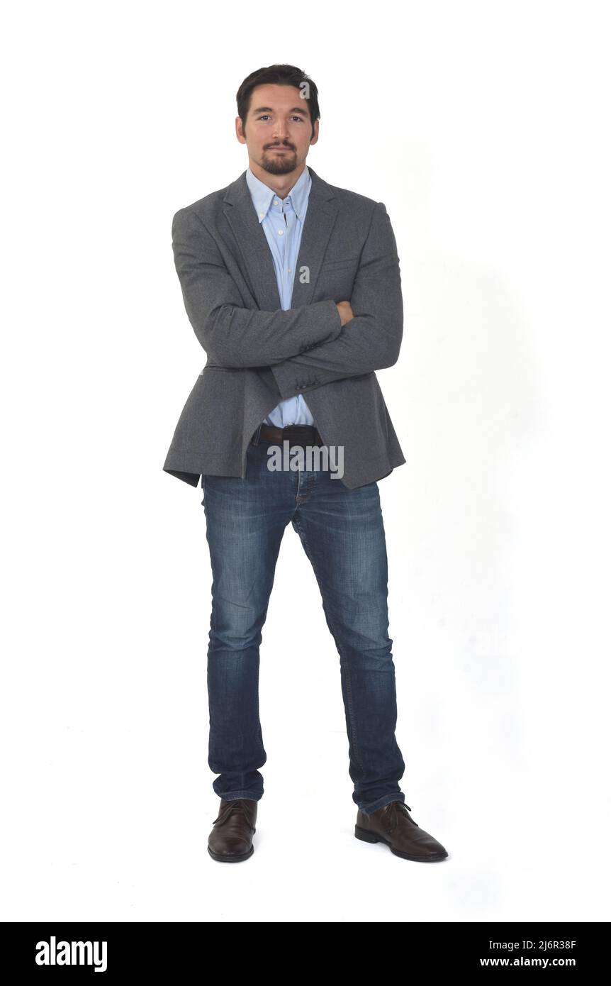 side view of a man with blazer and jeans with arms crossed on white ...