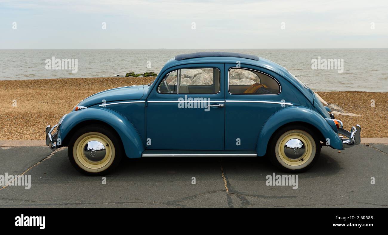 Classic Blue VW Beetle parked on seafront promenade with sea and beach ...