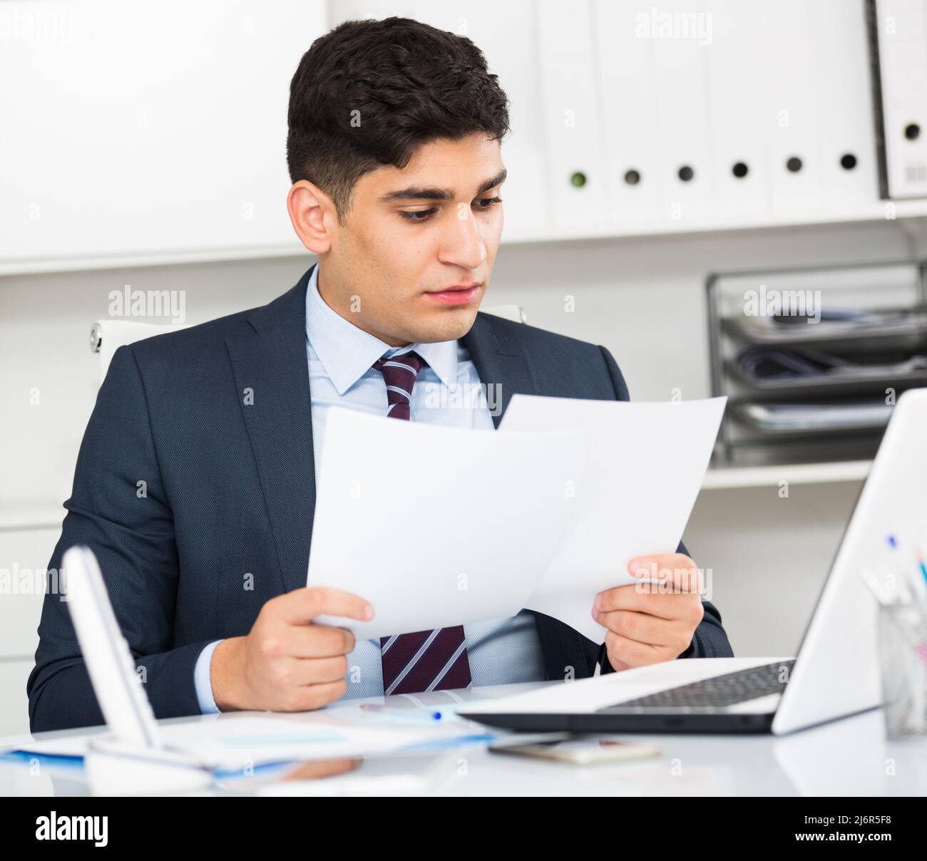 Young office worker is reading documents about the transaction Stock ...