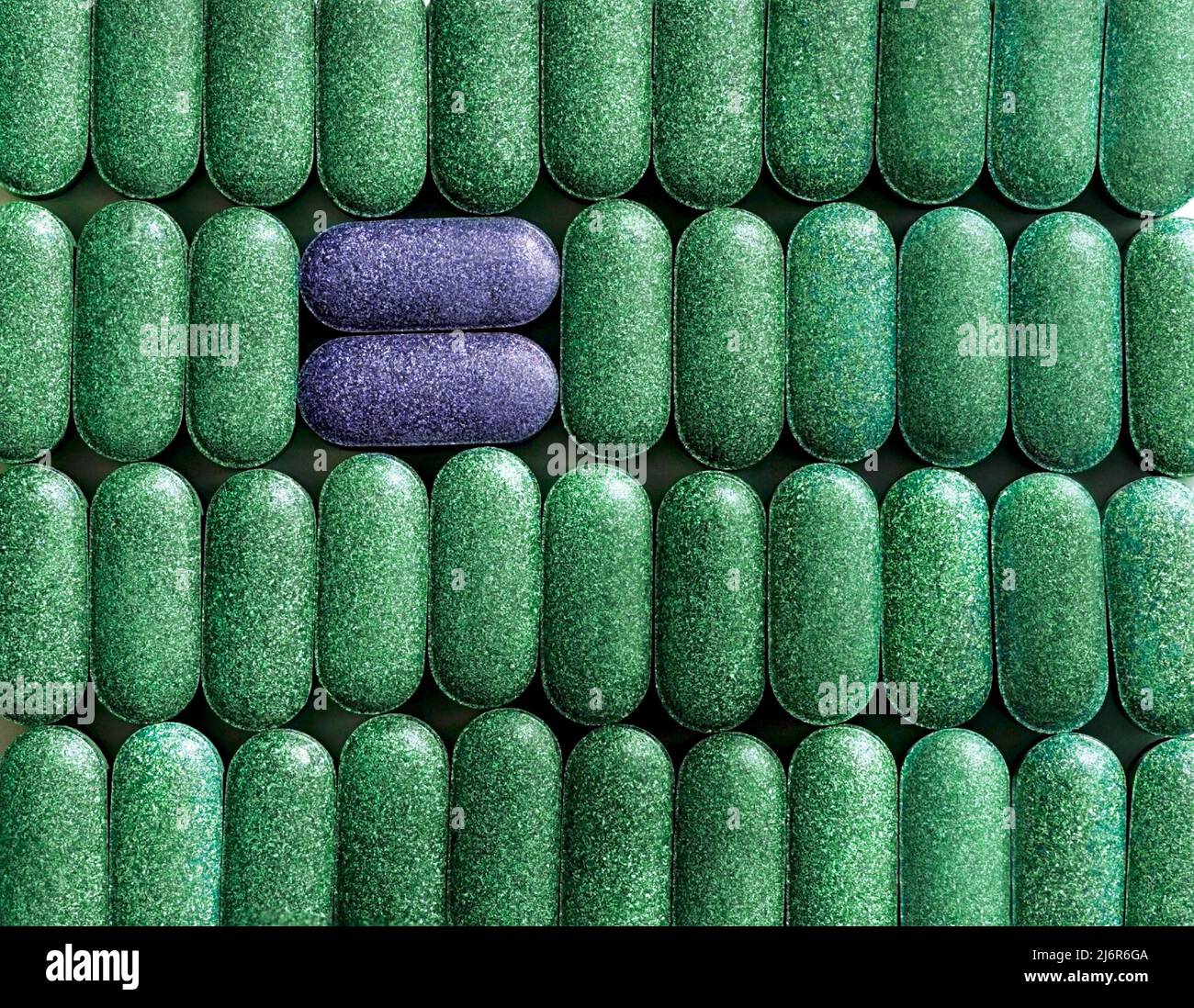 Chlorella, spirulina or barley grass in pill shaped rows and two purple ...