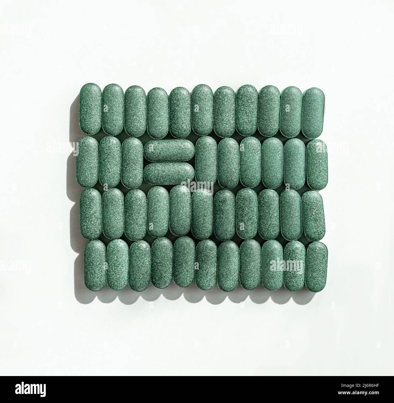 Chlorella, spirulina or barley grass in pill shaped rows and two pills ...