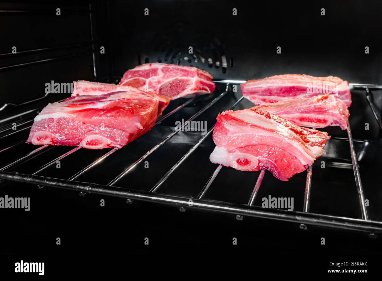 Uncooked beef ribs on grill plate in electric oven - close up Stock ...