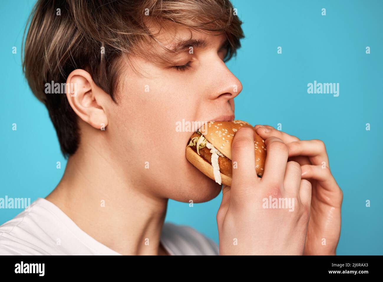 Very hungry young man holding tasty hamburger Stock Photo - Alamy