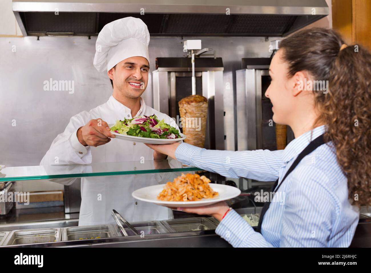 Happy professional chef and young waitress taking kebab for client ...