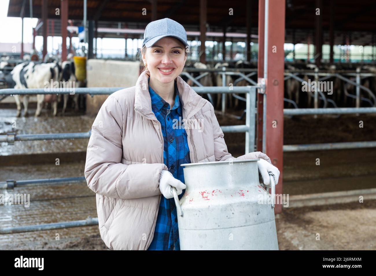 Female farmer standing near cowshed at dairy farm with milk churn Stock ...