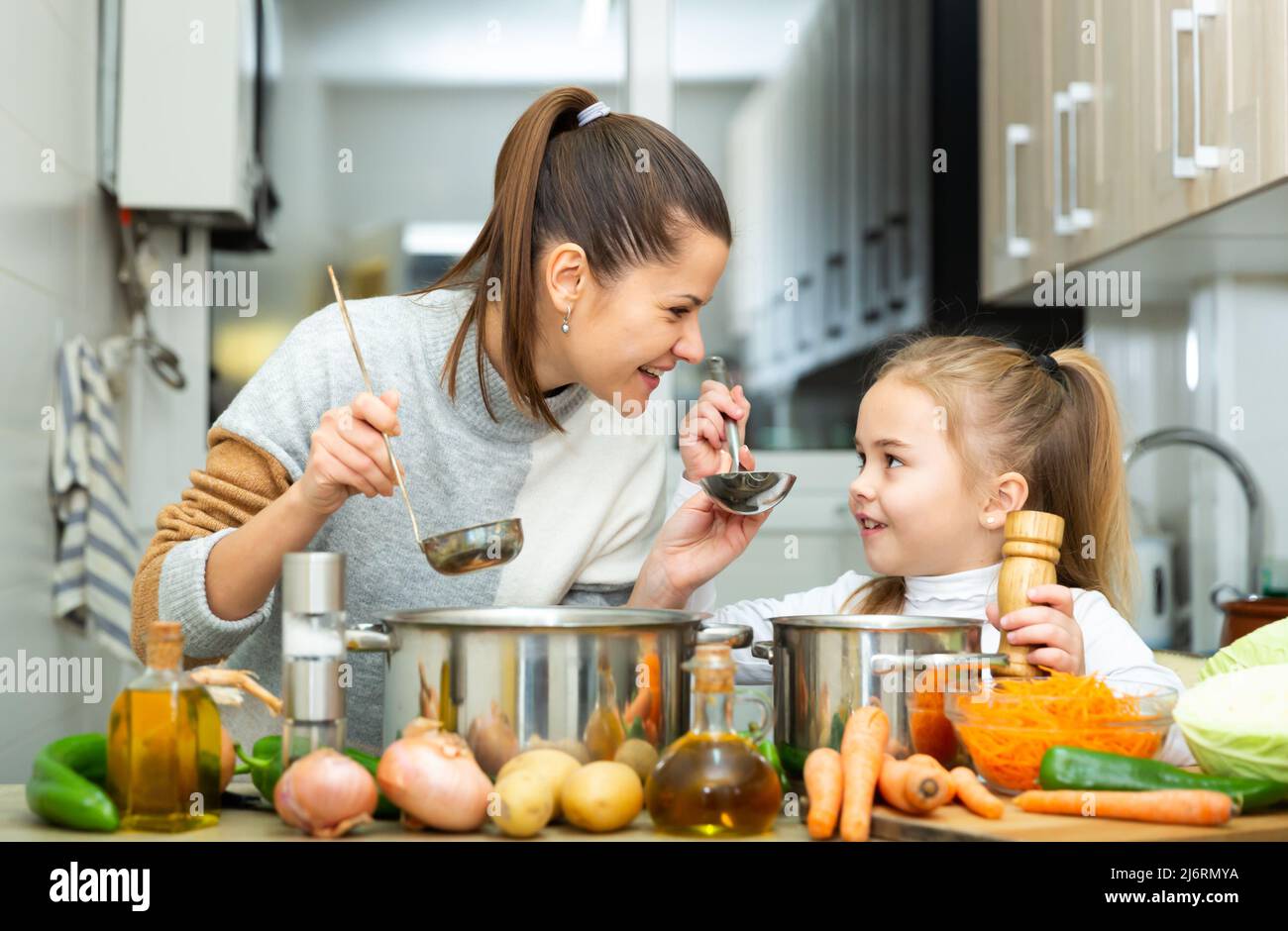 Happy young mother and daughter tasting vegetable soup Stock Photo - Alamy